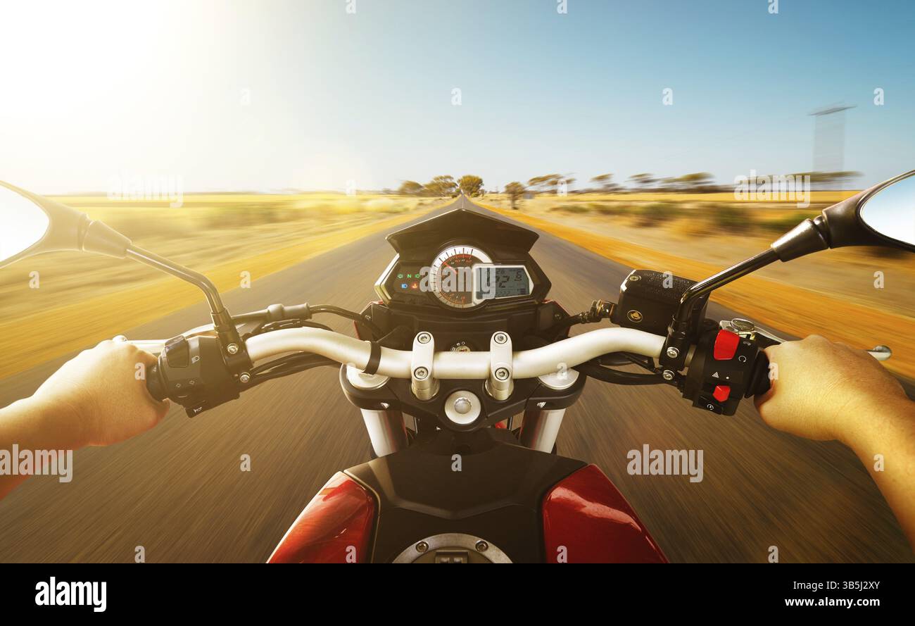 Biker driving a motorcycle rides along the country road, morning scene ...