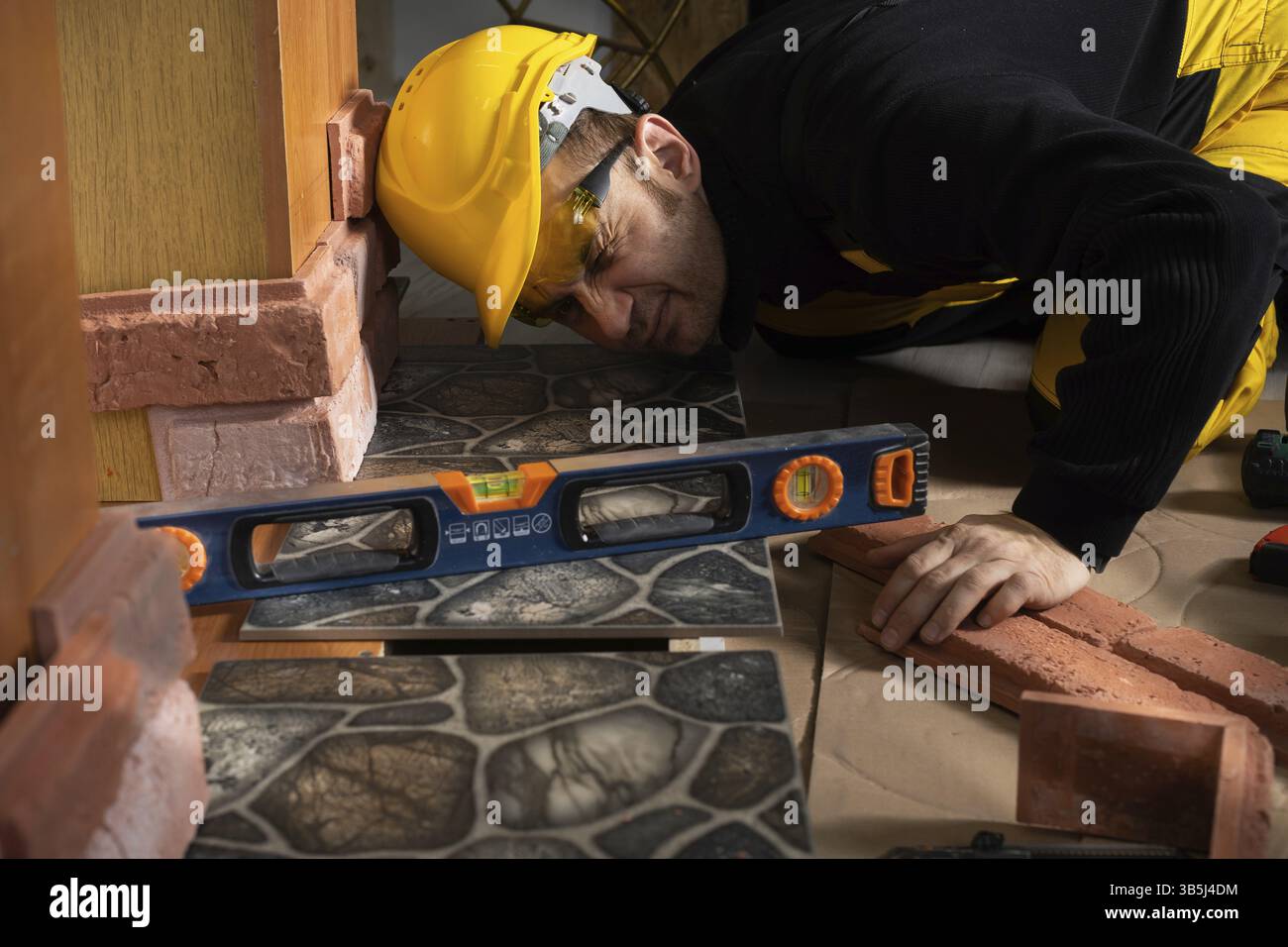 While laying the terracotta, the general construction worker checks the correctness of execution ...