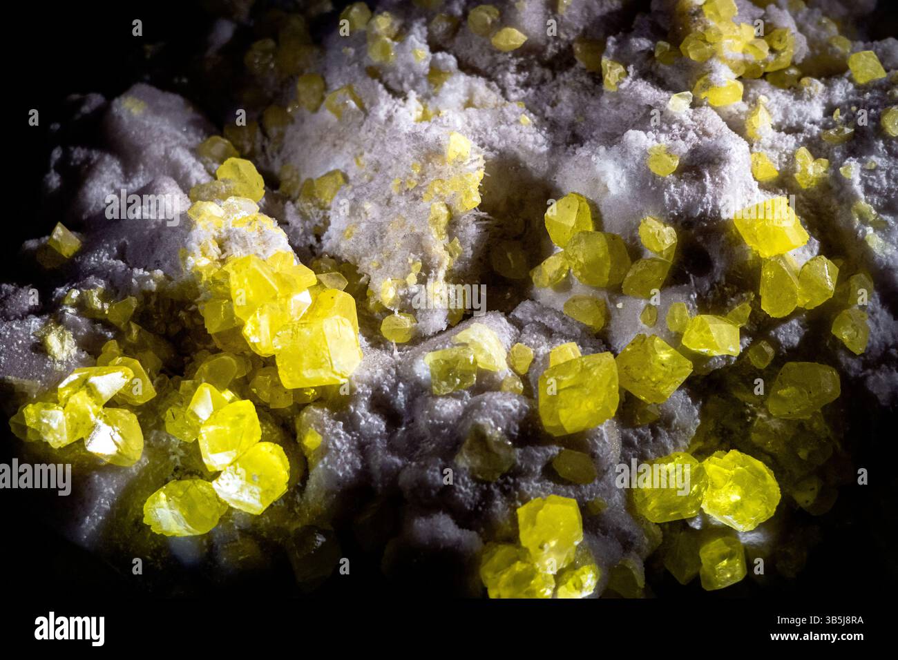 Macro photograph of vivid yellow sulfur crystals formed on a white ...