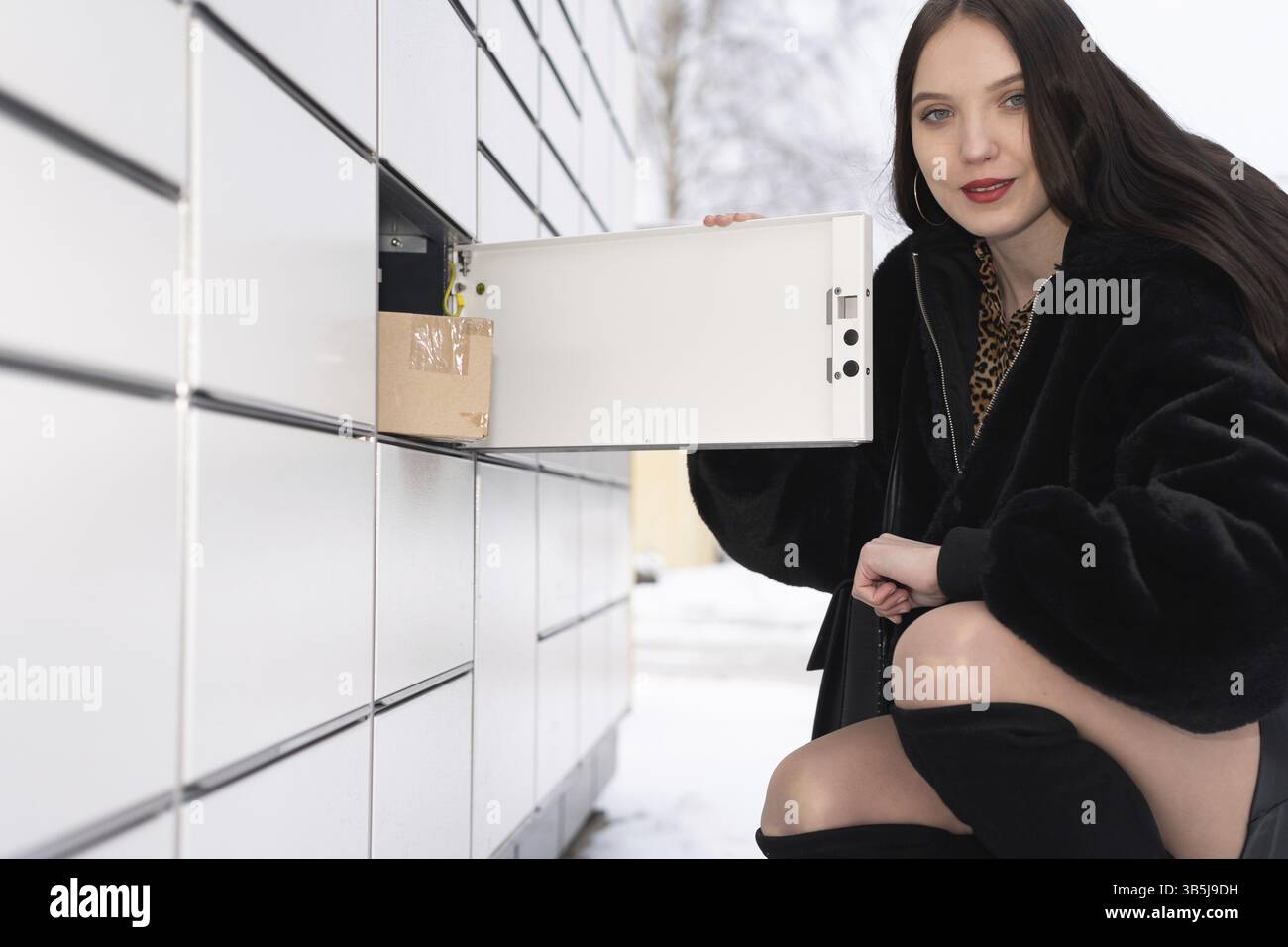 An attractive young adult collects a package from a parcel locker in ...