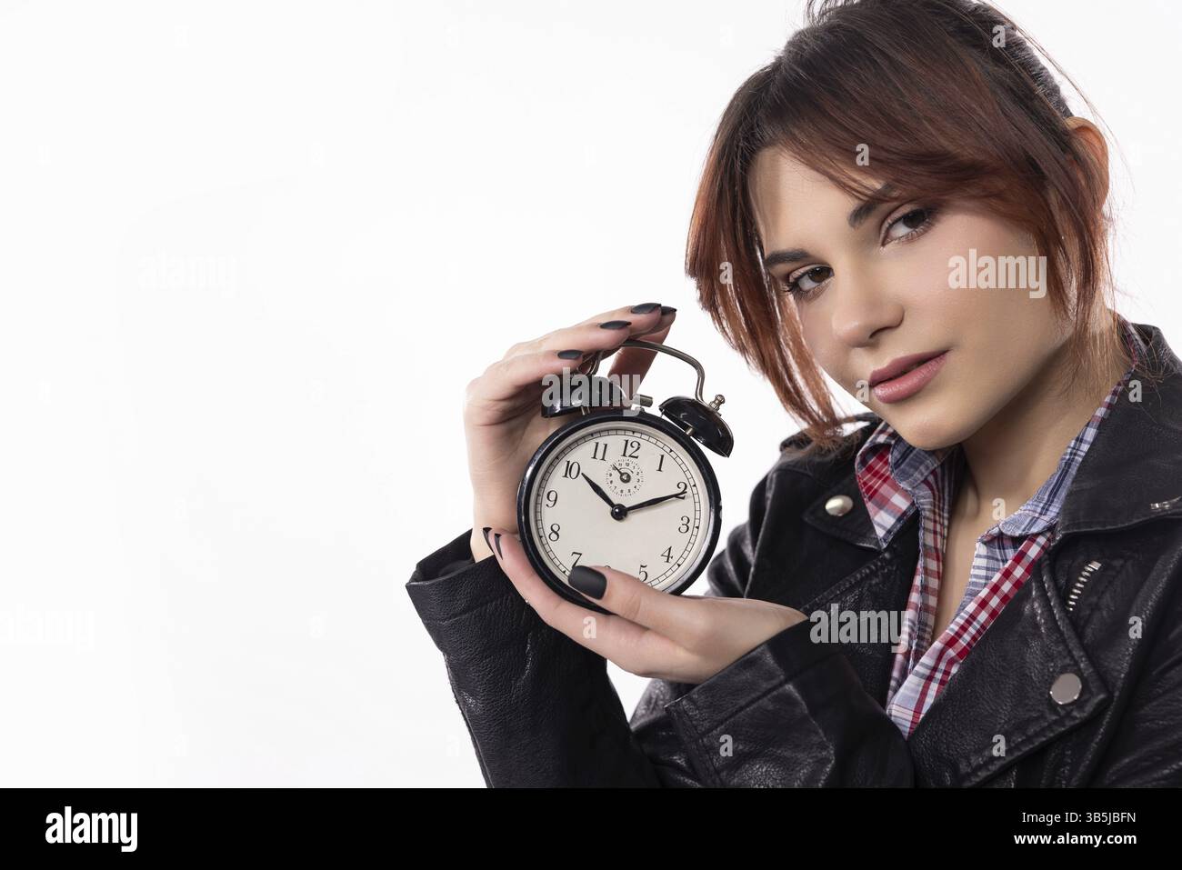 A young woman poses with a stylish alarm clock, highlighting her trendy ...