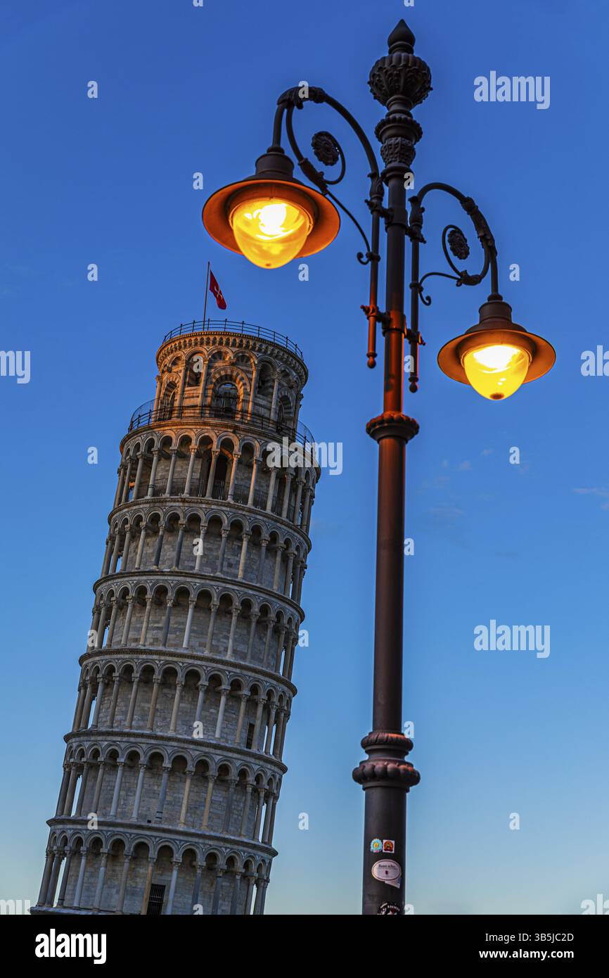 The Leaning Tower under an illuminated street lamp in the evening light ...