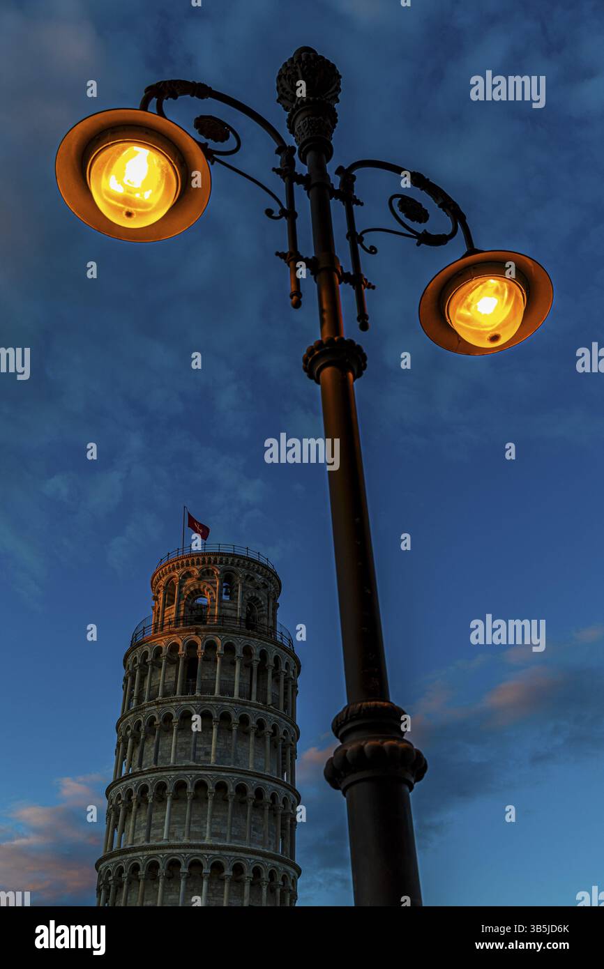 The Leaning Tower under an illuminated street lamp in the evening light ...