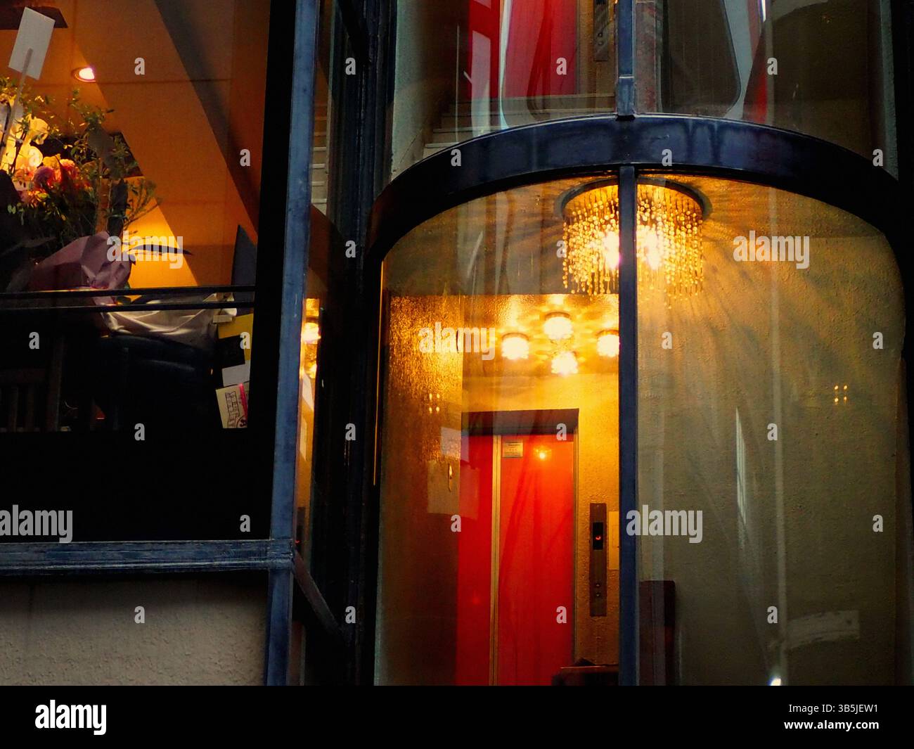 Elegant chandelier and interior flowers seen through curved glass ...