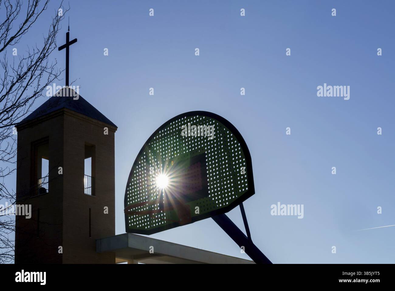 Sun shining through a basketball hoop in front of a church tower Stock ...