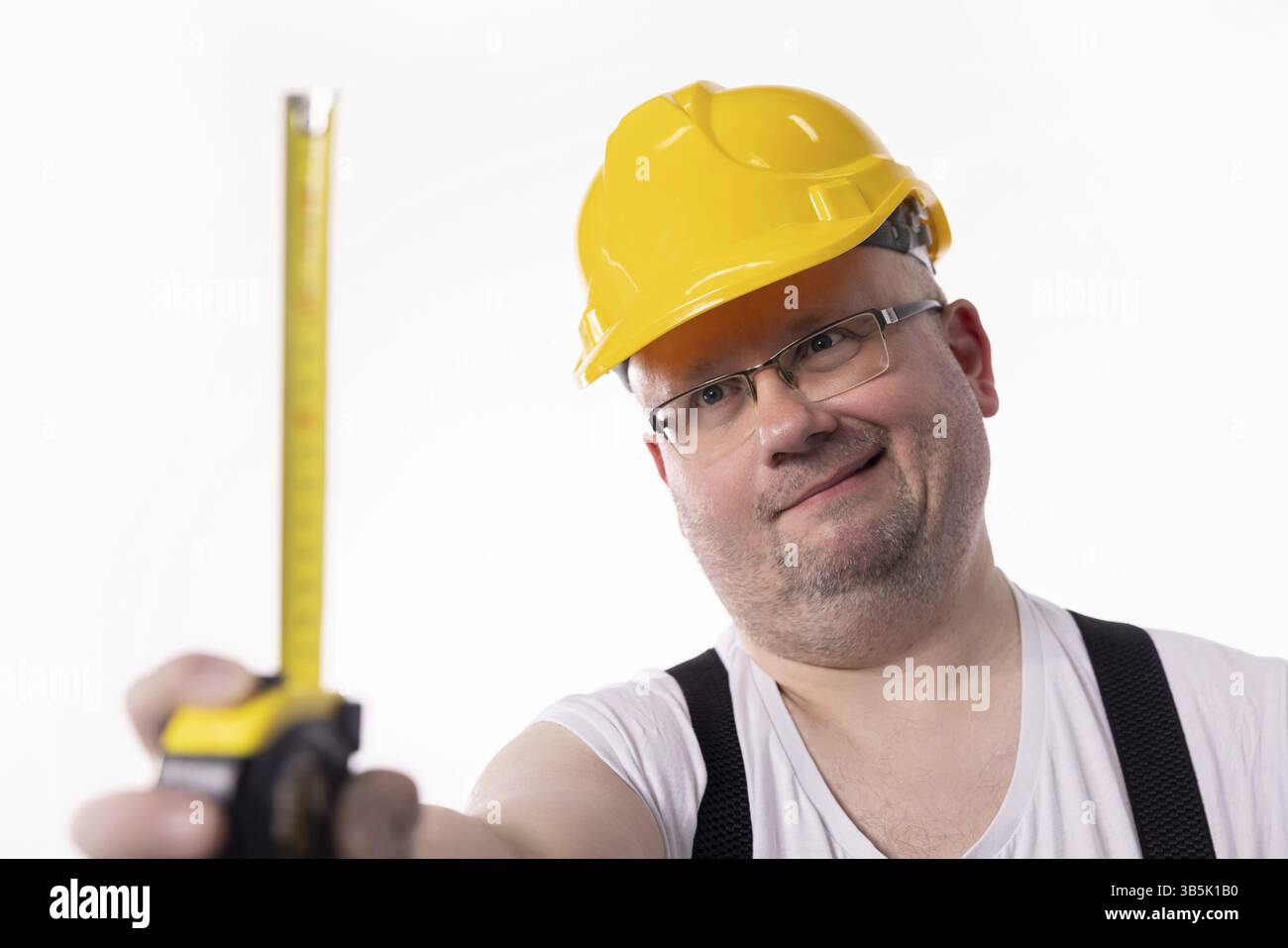 A cheerful and skilled construction worker holds a measuring tape in ...