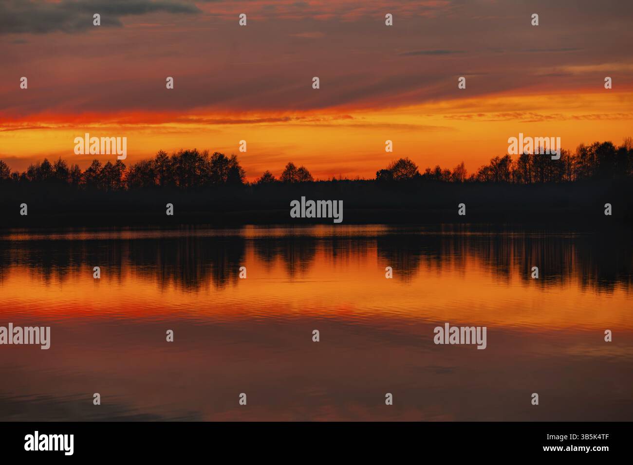 A picturesque sunset casts vibrant colors over a tranquil lake ...