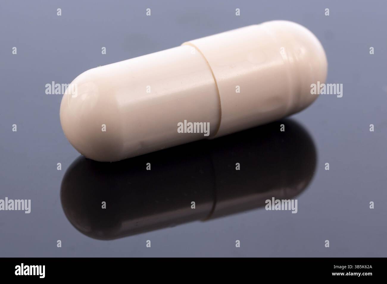 Single white capsule isolated on black reflective surface. Global ...