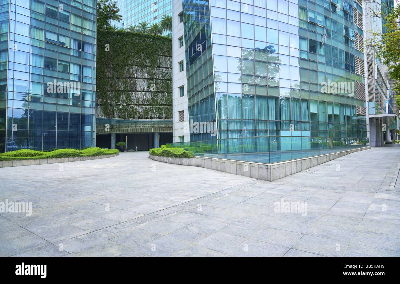 Empty square with green bushes and modern office buildings with glass ...