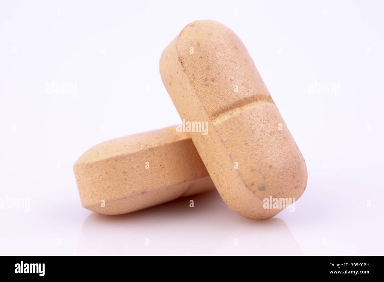 Two beige pills isolated on white reflective background. Global ...