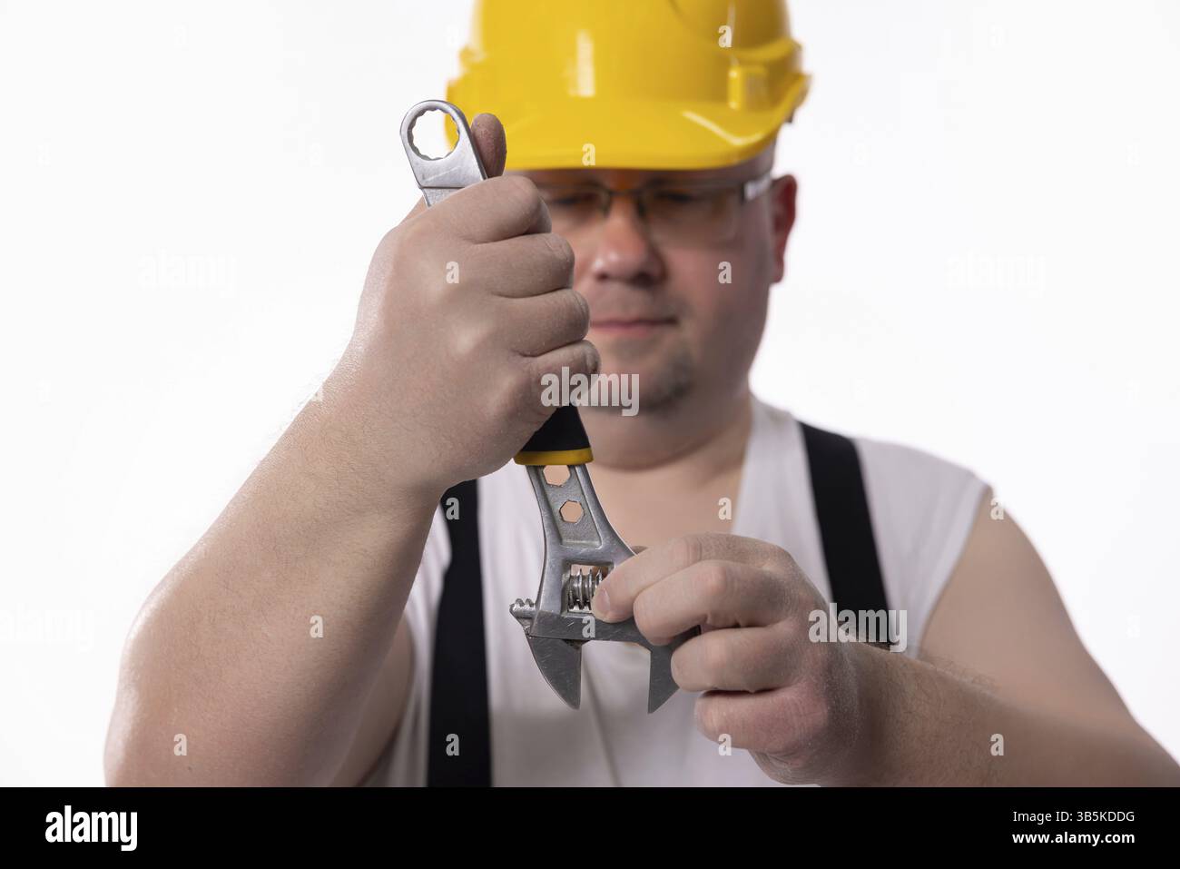 A construction worker expertly uses an adjustable wrench, demonstrating ...