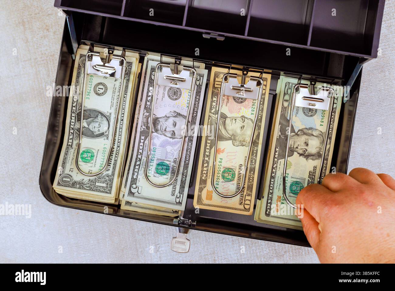 Hand retrieves US dollars cash from an organized money box with neatly ...