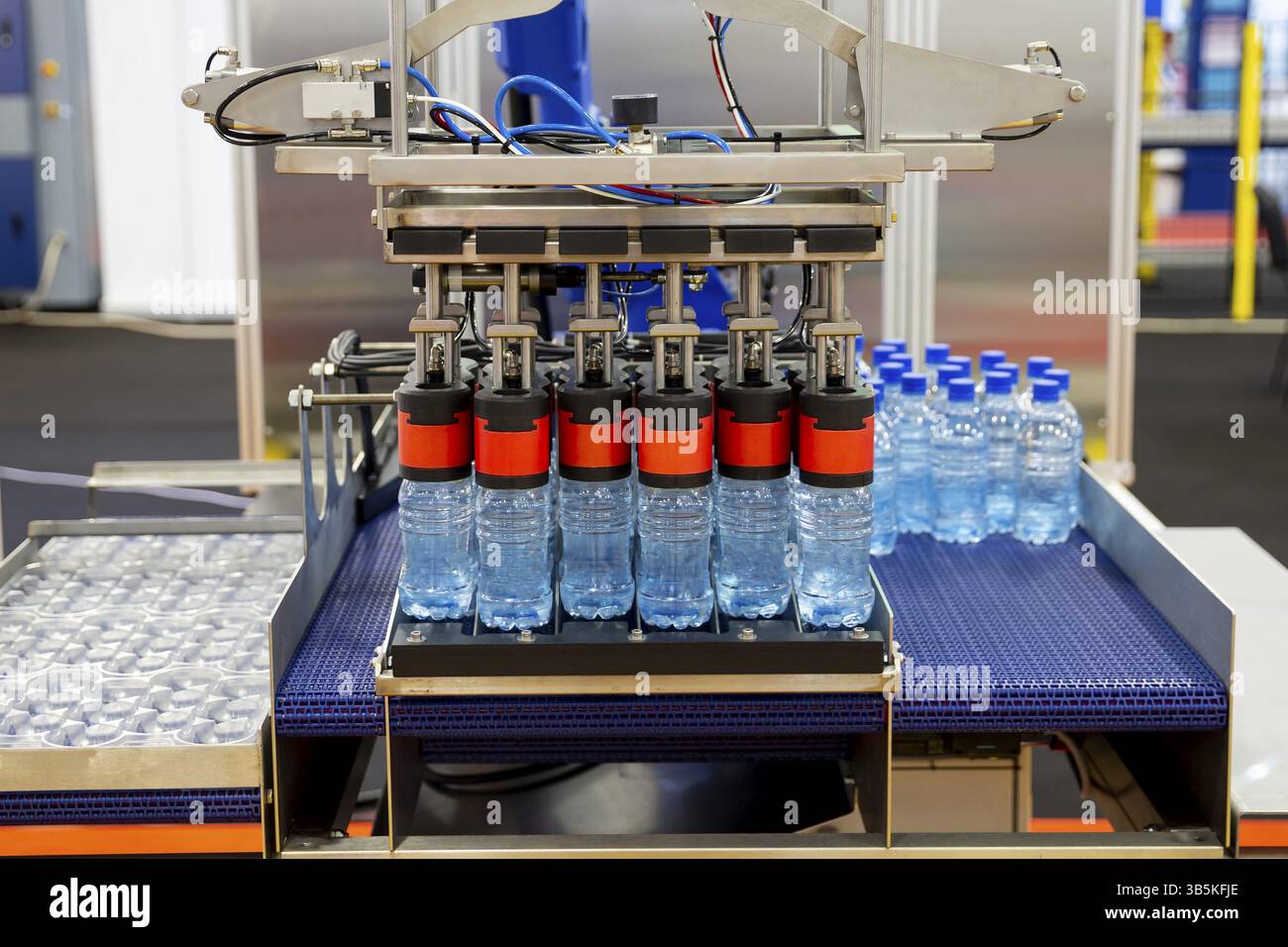 Robotic arm arranges plastic water bottles in Ð° packing case ...