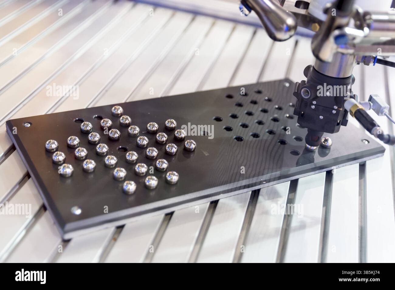 A robotic mechanical arm arranges small metal balls. The machine is demonstrating its speed and ...