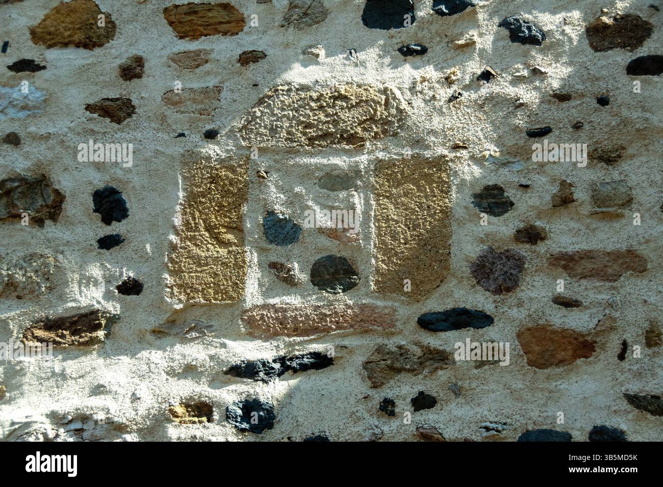 A weathered stone wall displays a distinct pattern made of varied ...