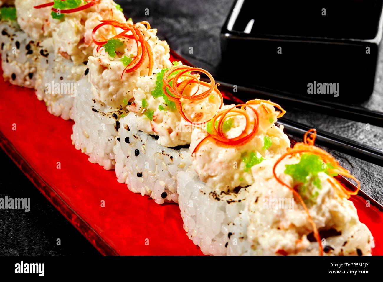 Uramaki sushi rolls are served on a red plate, featuring a cream cheese ...