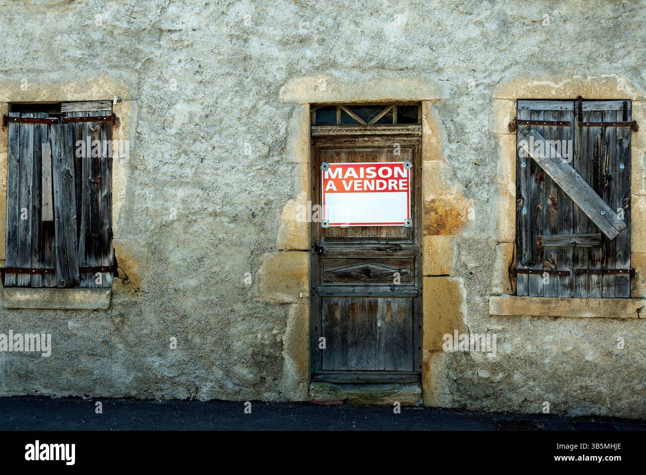 A rustic stone house features a weathered facade and boarded windows. A ...