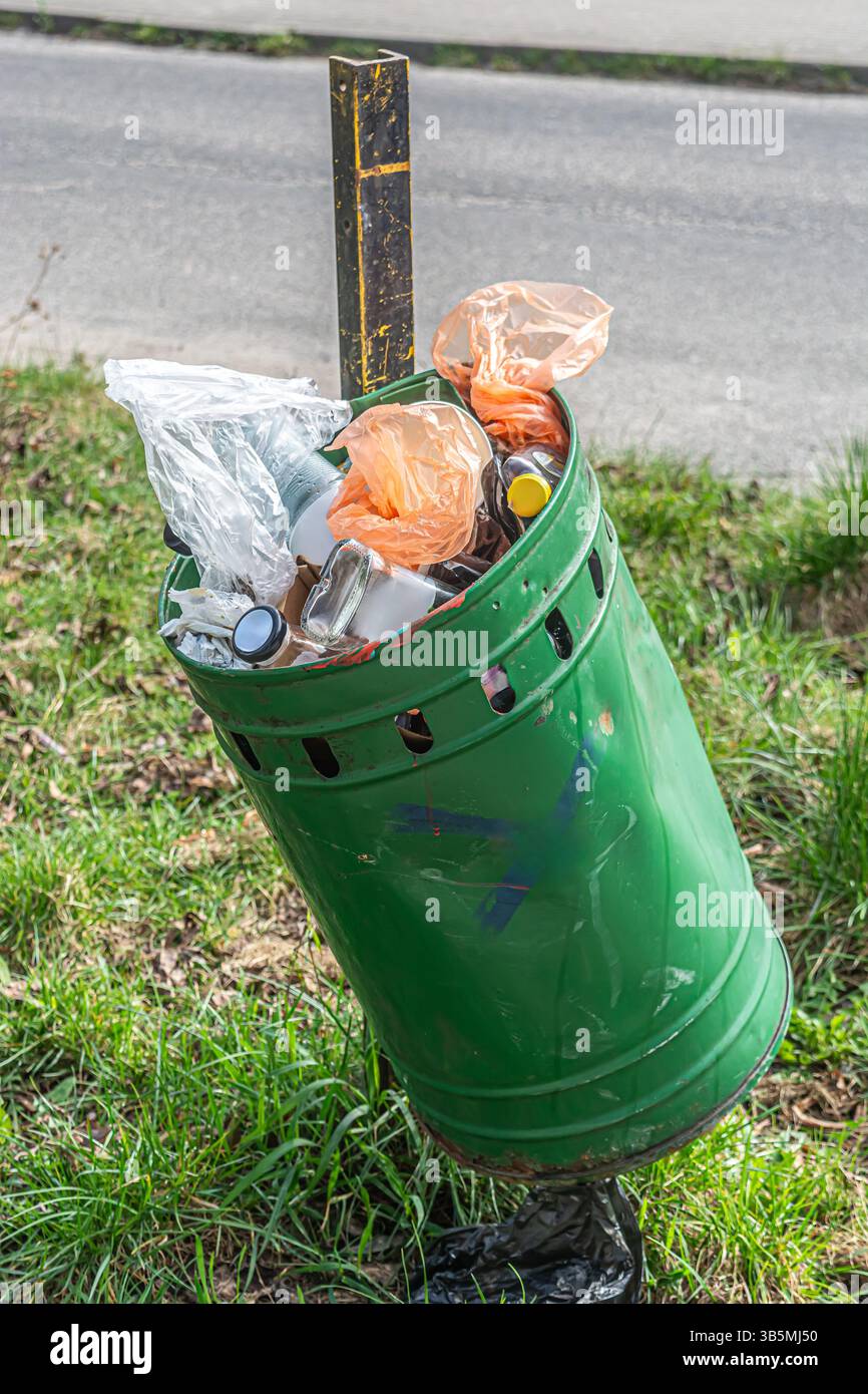 Overflowing trash can and litter scattered along the pathway Stock ...