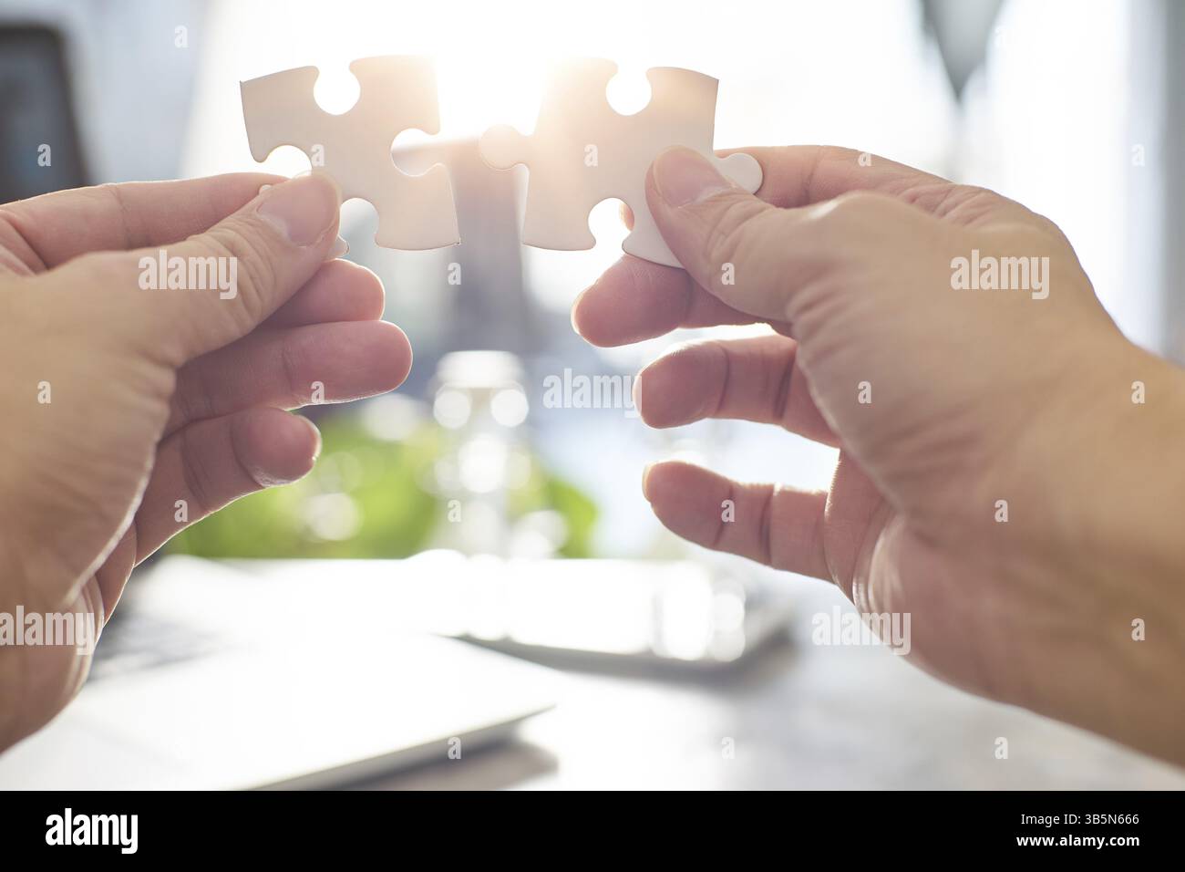 Young businessman trying to connect couple puzzle piece with sun flare ...
