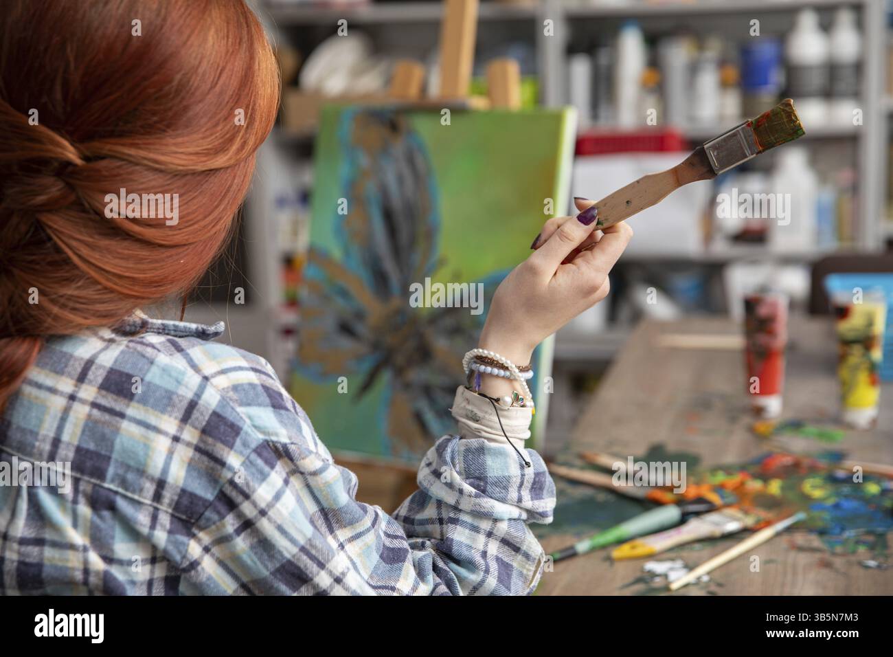 An artist focuses on her vibrant canvas, showcasing her creativity and ...