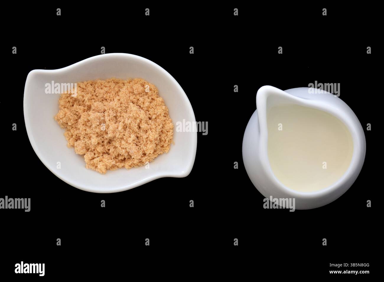 Cream and golden sugar in white dishes on black background from ...