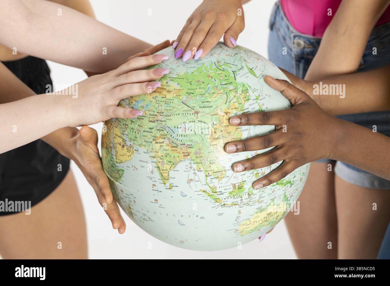 A large globe with all continents is supported by female hands of ...