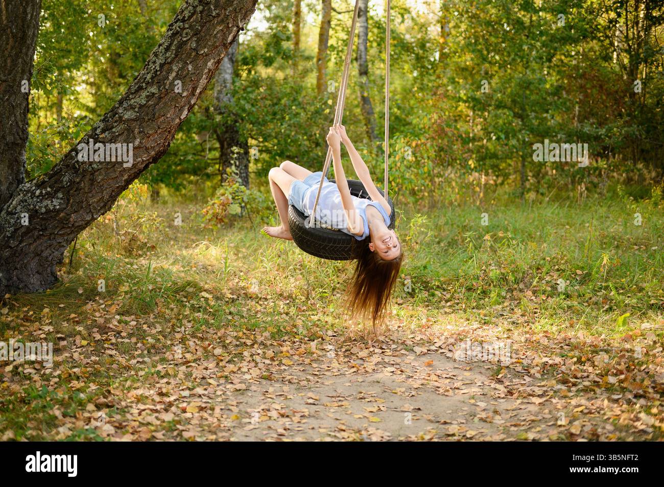 Girl swings on homemade swing hanging from tree, smiling happily, with ...