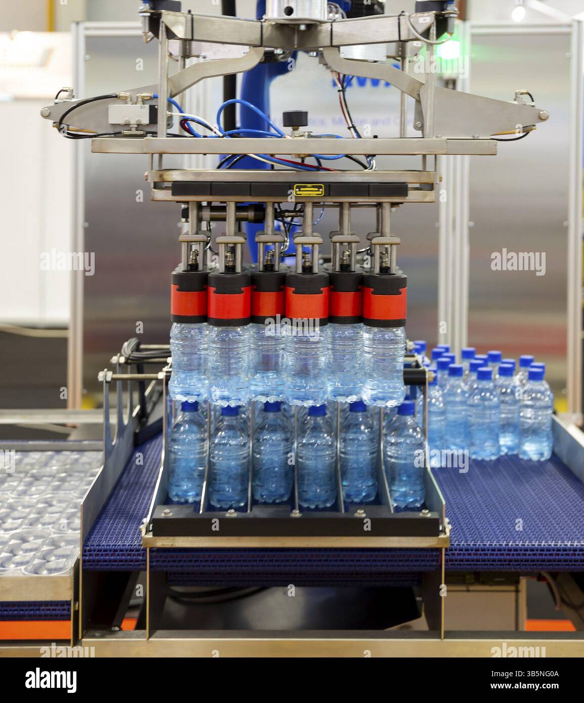 Robotic arm arranges plastic water bottles in Ð° packing case ...