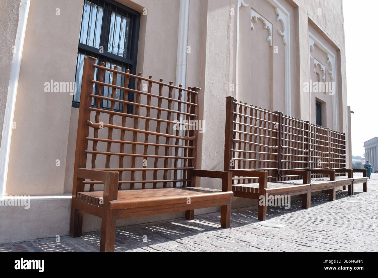 Elegant wooden benches with lattice backrests line the cobblestone ...