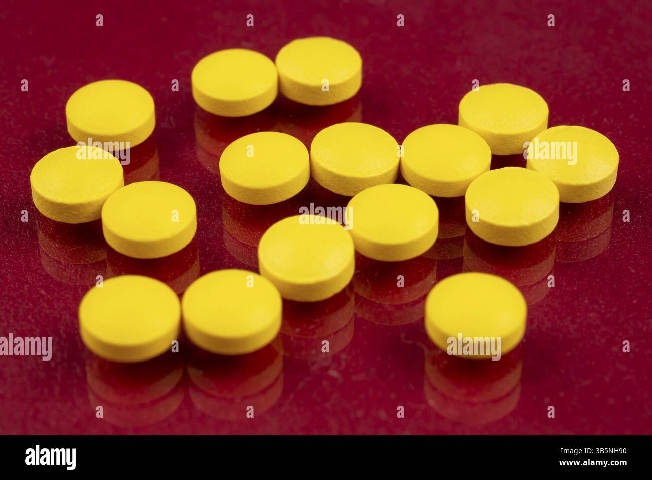 Yellow vitamin C pills isolated on a red reflective background. Global ...