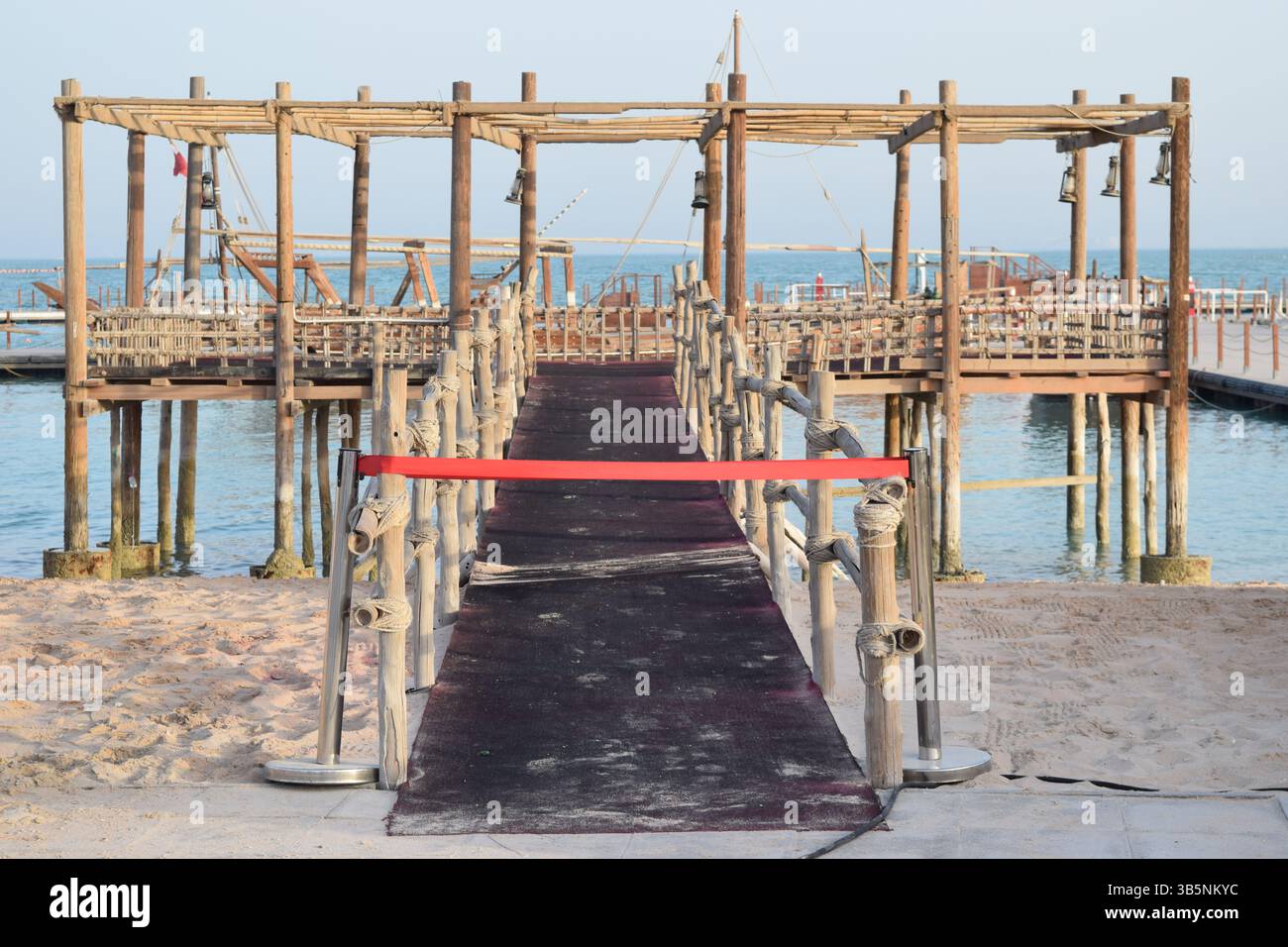 A red carpet walkway leads to a wooden pier and marina, creating an ...