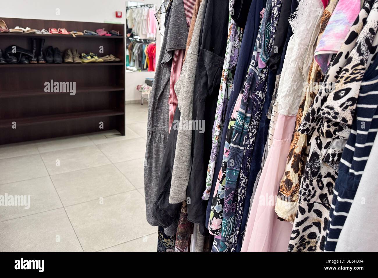 dresses hang on a rack inside a clothing store with shelves of shoes in ...