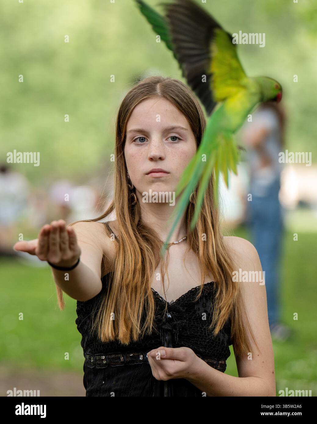 London, England, UK. 2nd May, 2025. A woman feeds a rose-ringed ...