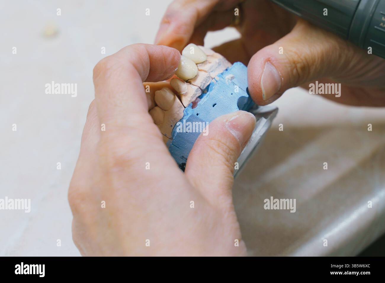 A skilled dental technician meticulously works on a jaw model to ...
