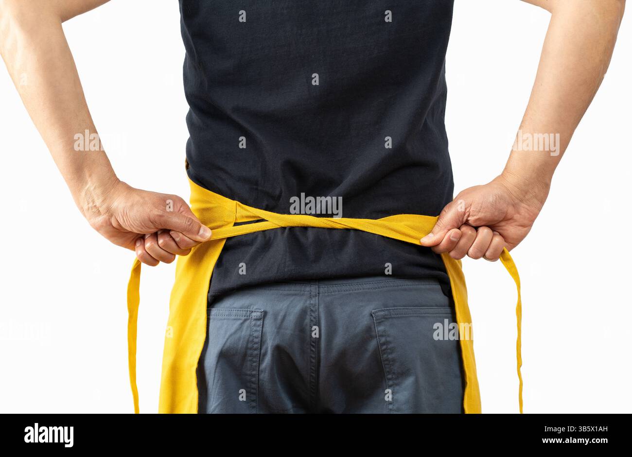 Rear view shot an unidentifiable man tying his yellow apron behind his ...
