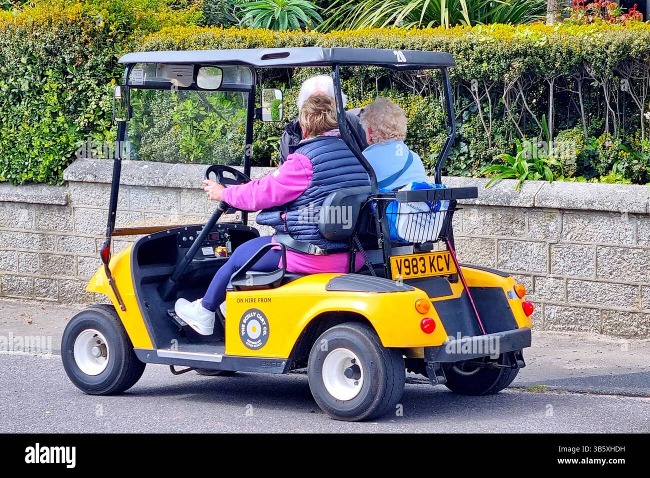 Rear view of two unrecognized women in a yellow golf buggy, a popular ...