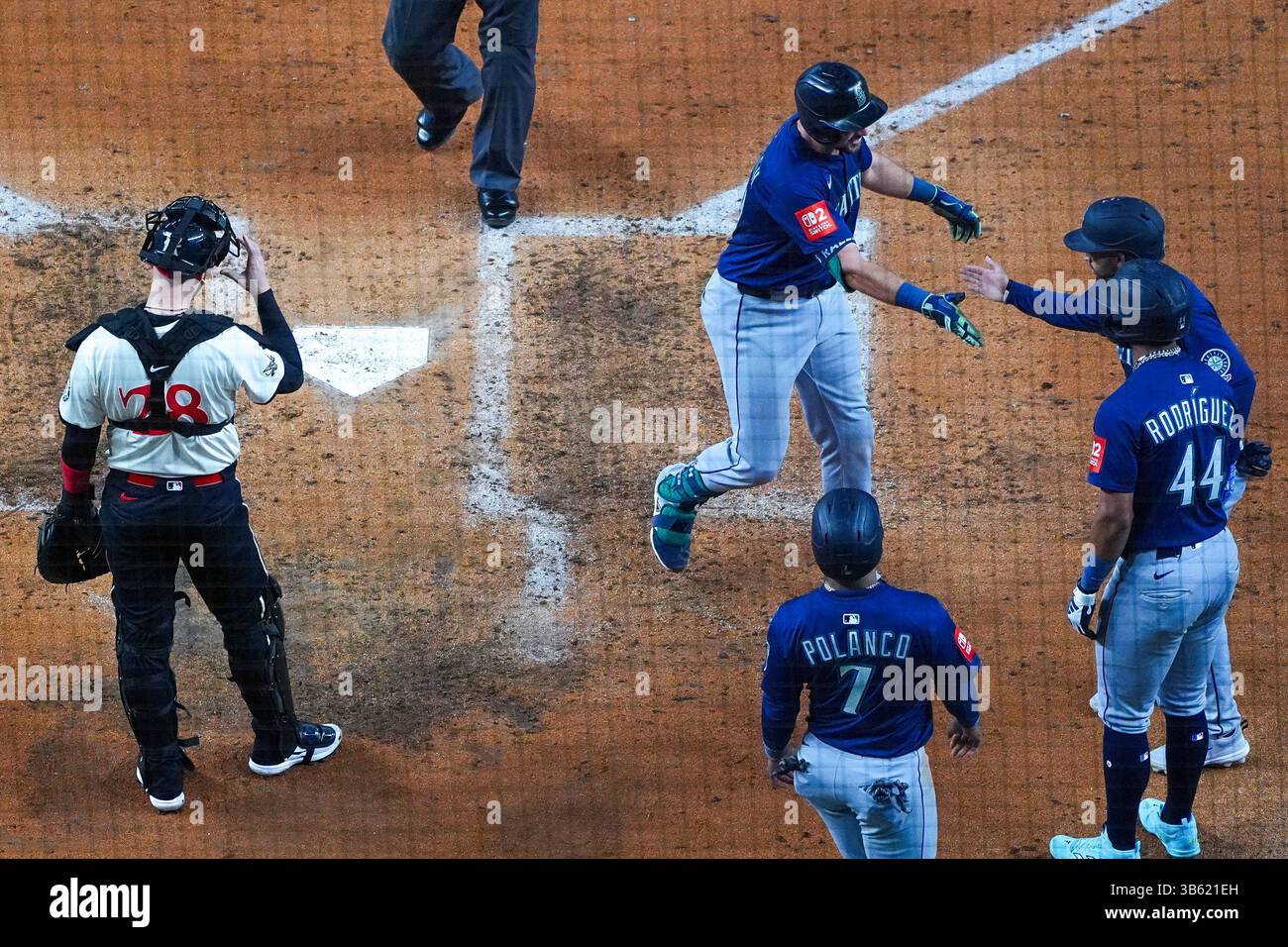 Seattle Mariners' Cal Raleigh, center, is greeted near home plate by ...