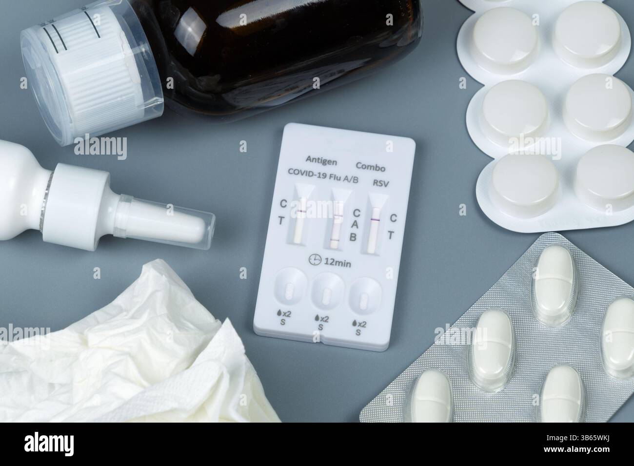 Flu test, pills, cough syrup, nasal spray and tissues on gray ...