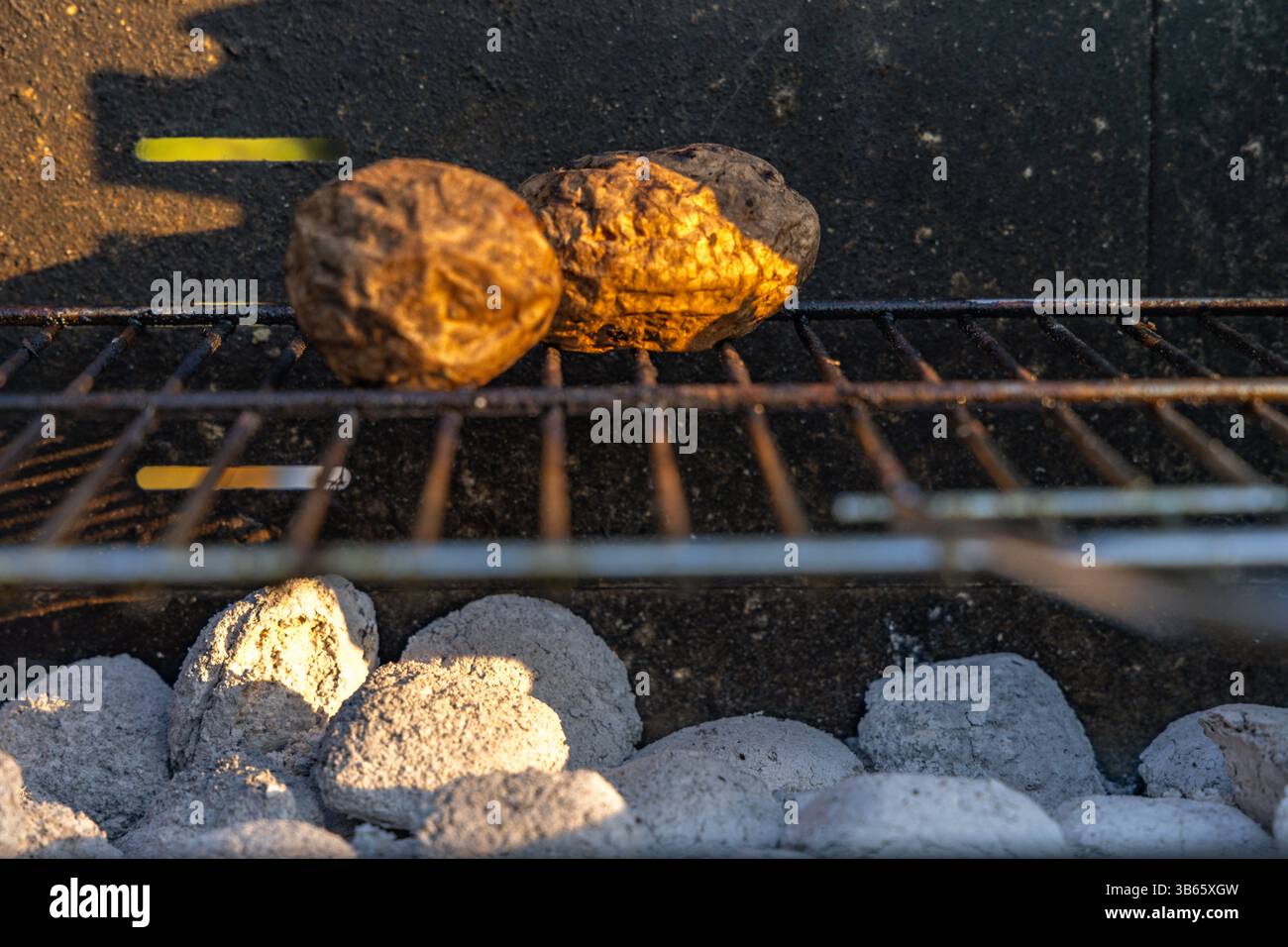 Two baked potatoes on the grill, fried potatoes in their skins from the ...