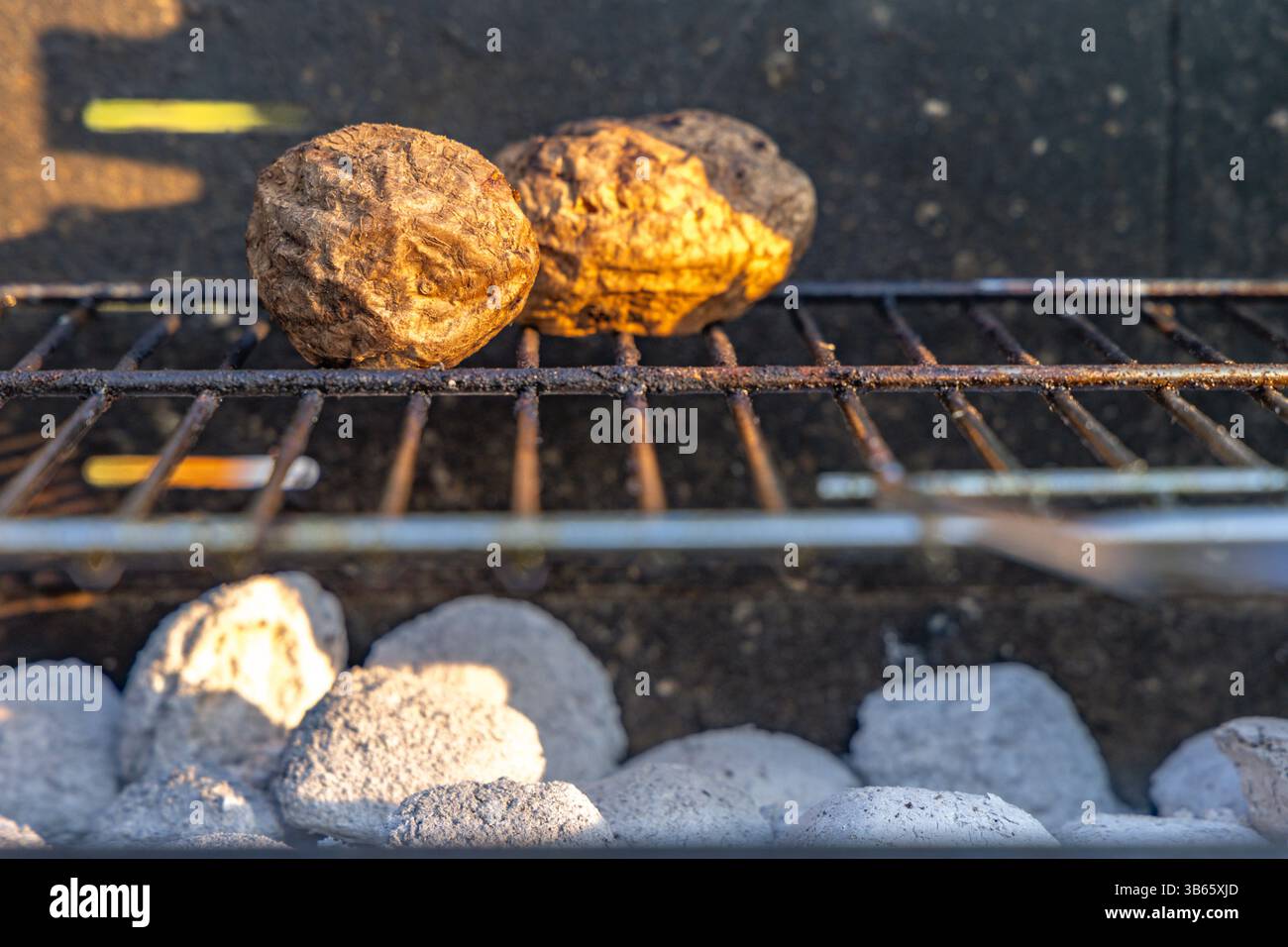 Two baked potatoes on the grill, fried potatoes in their skins from the ...