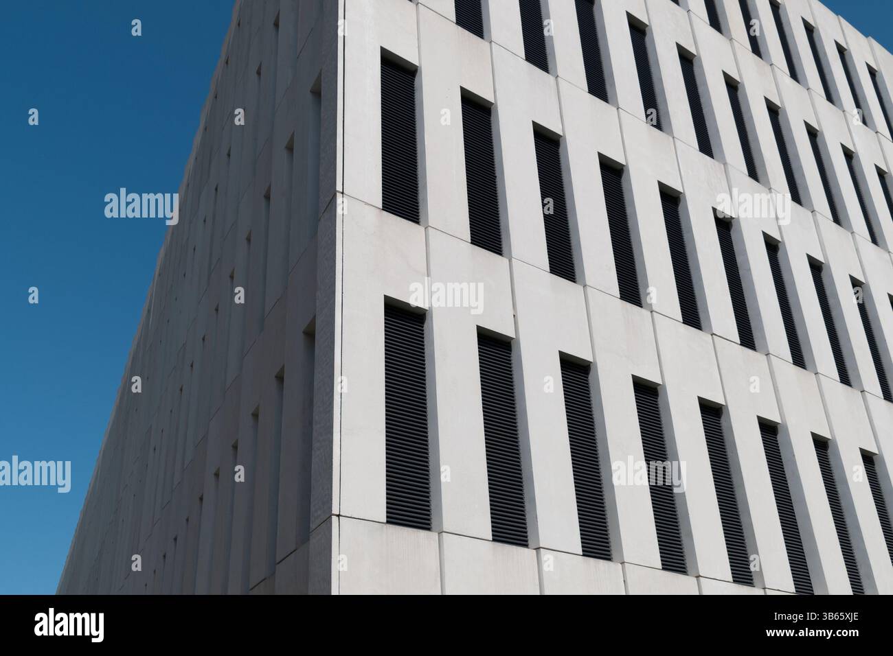 Modern concrete building facade with vertical narrow windows against a ...