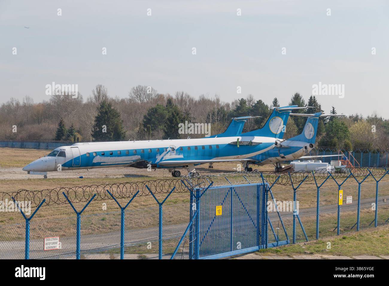 Two abandoned blue and white airplanes with missing engines sit behind ...