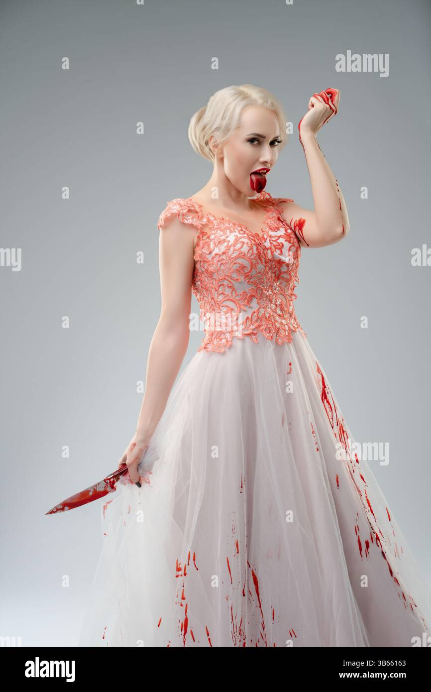 Bride in a blood-soaked dress posing dramatically in a studio setting ...