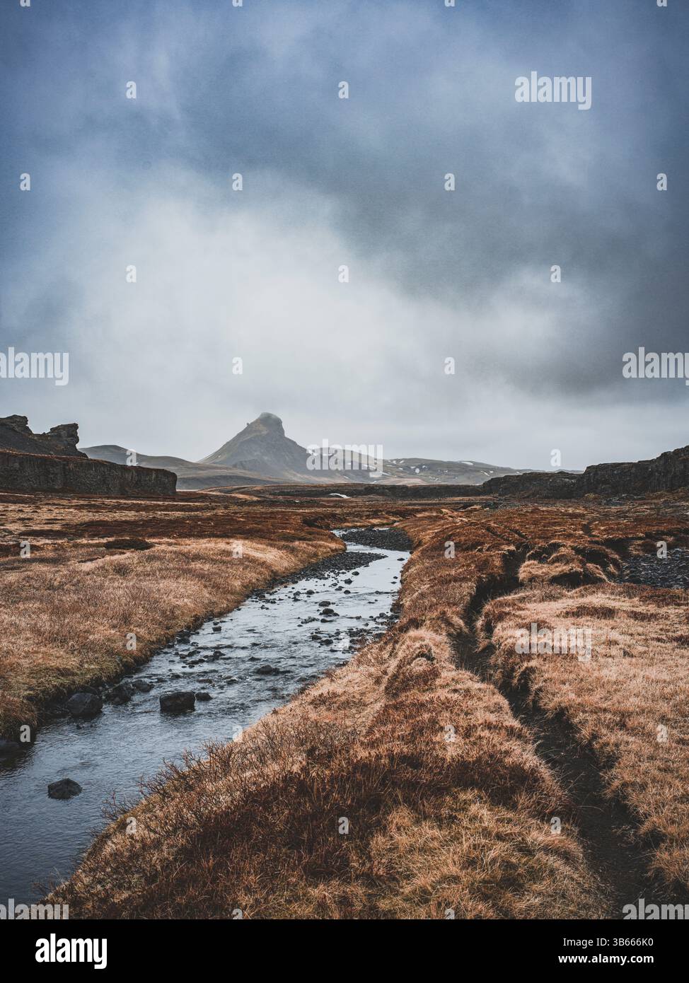 Winding stream through barren Icelandic highlands under a moody sky on ...