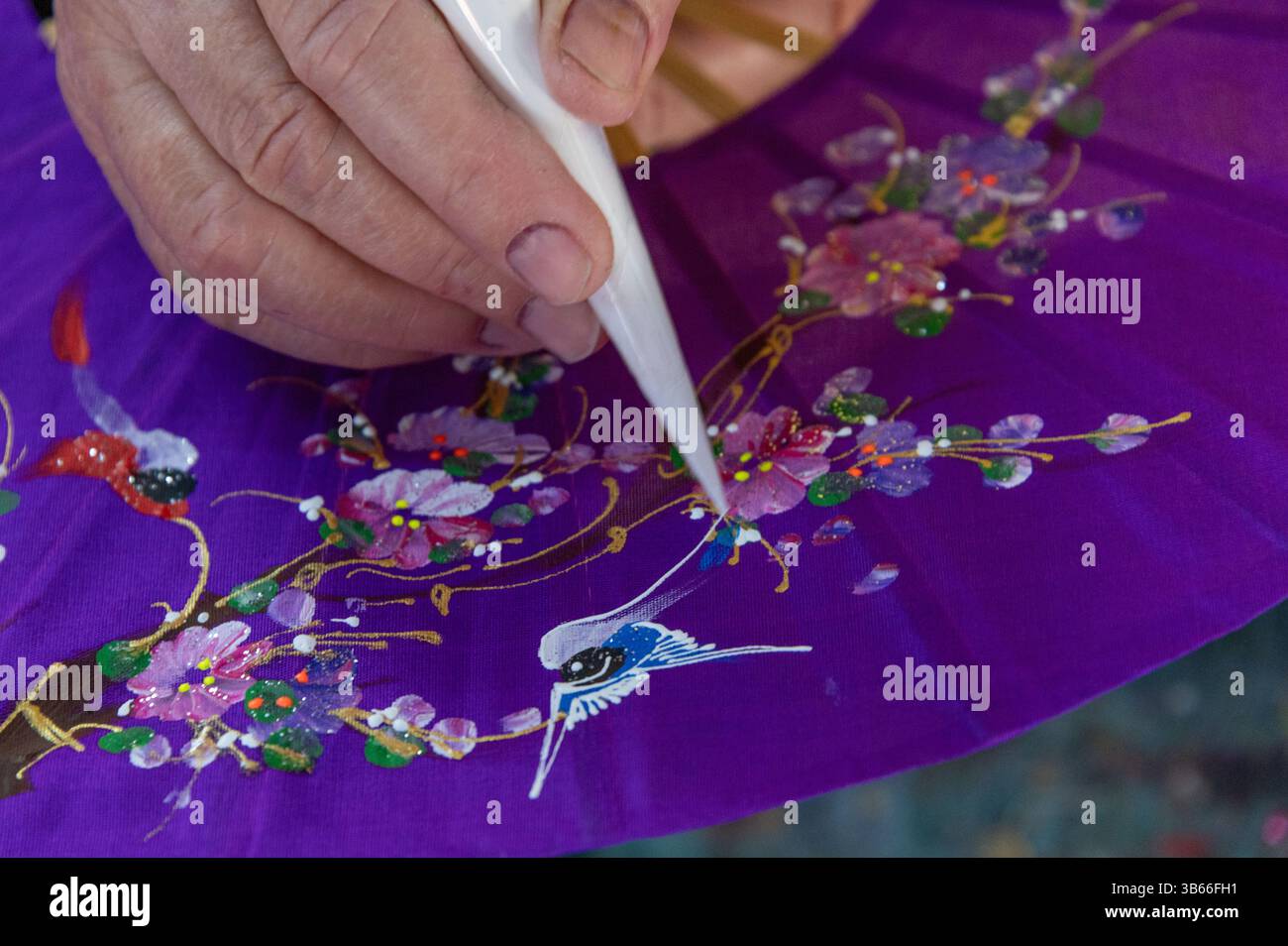 An artist painting a hand fan at the Bo Sang Umbrella village in Chiang ...
