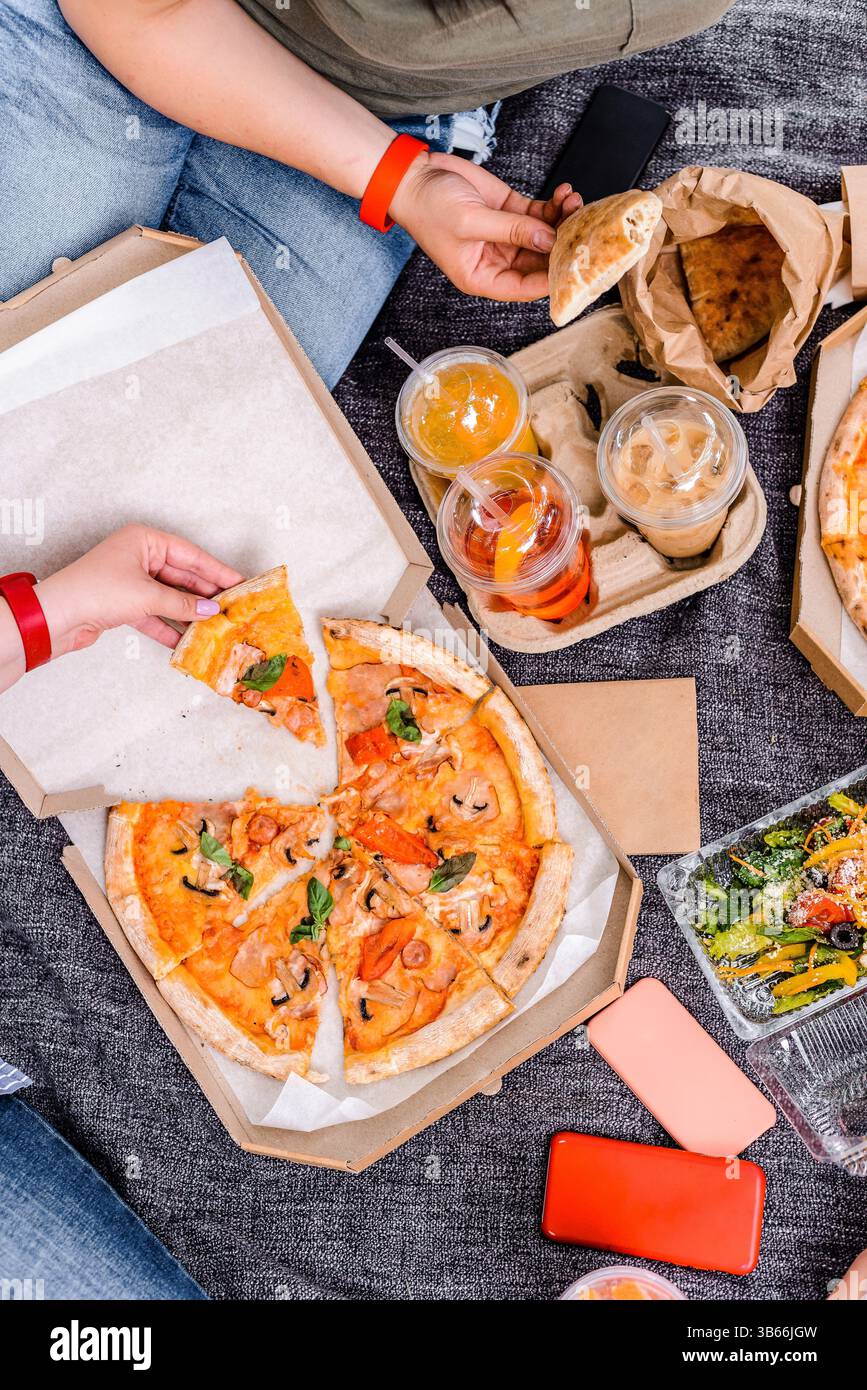 Hands taking slices of pizza close view. Friends eating pizza at the ...