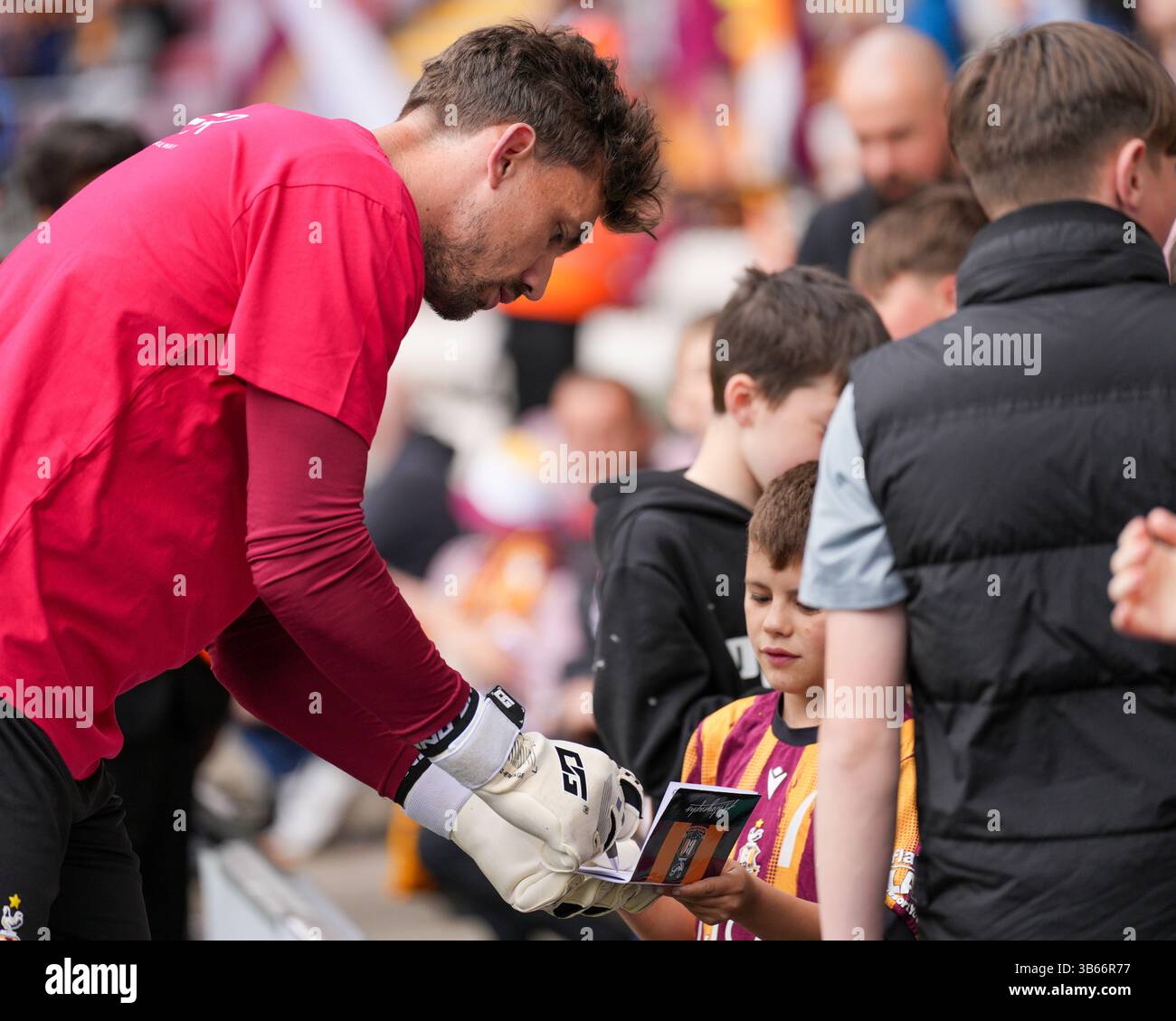 Sam Walker, goalkeeper for Bradford, signs an autograph for a young fan ...
