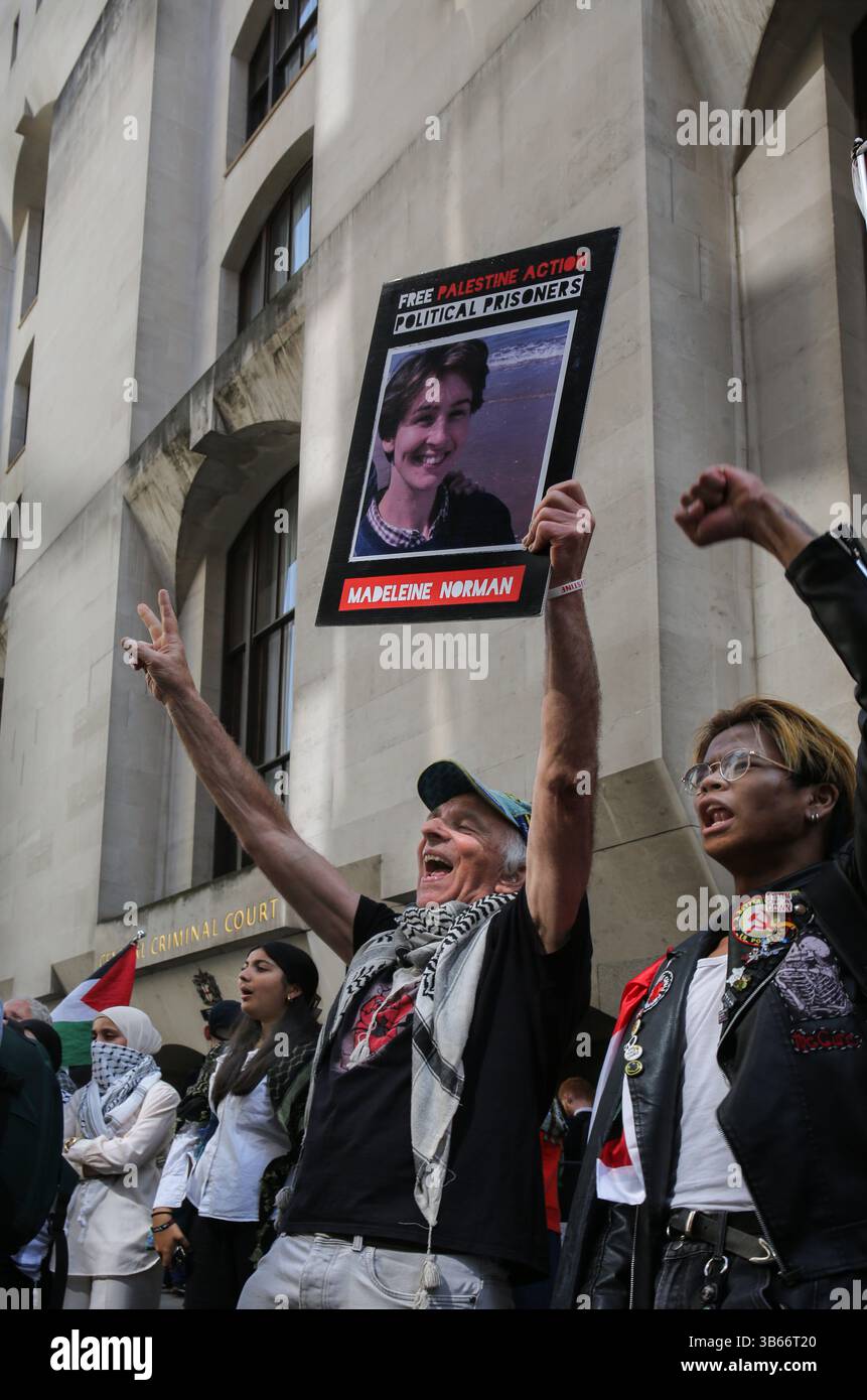 A protester gives a ‘V' for victory hand signal while holding a placard ...