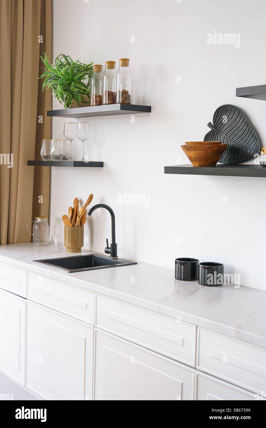 White kitchen with countertop and black water tap on white wall ...