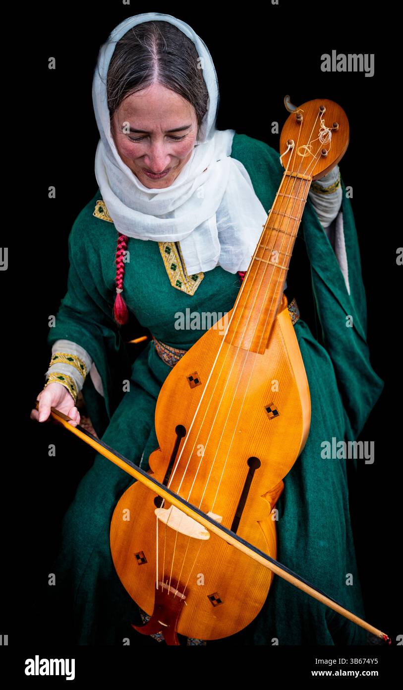 A female musician playing a medieval stringed instrument wearing ...